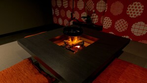 Quarto moderno com uma mesa central com lareira embutida, rodeada por bancos de madeira.