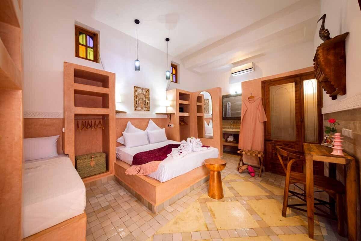 Quarto de hotel com cama, estantes de madeira, escrivaninha e cadeira.