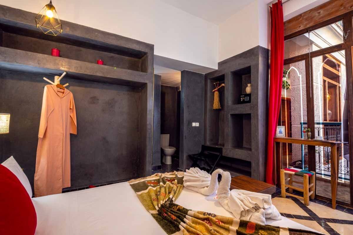 Quarto de hotel com cama, roupão pendurado, porta-toalhas, uma pequena mesa e vista para o exterior.