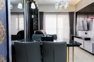 Uma sala de estar moderna com área de jantar, sofá, televisão e lustre.