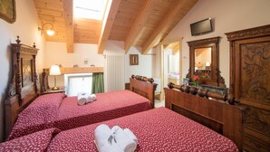 Quarto com duas camas, móveis de madeira, televisão e janela com vista.