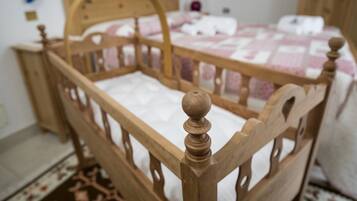 Uma cama de madeira com cabeceira e peseira, uma mesinha de cabeceira e um cobreleito estampado.