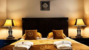 Quarto de hotel com uma cama grande, duas luminárias de cabeceira e um quadro na parede.