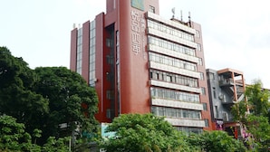 Um edifício de vários andares com fachada vermelha marcante e várias varandas.