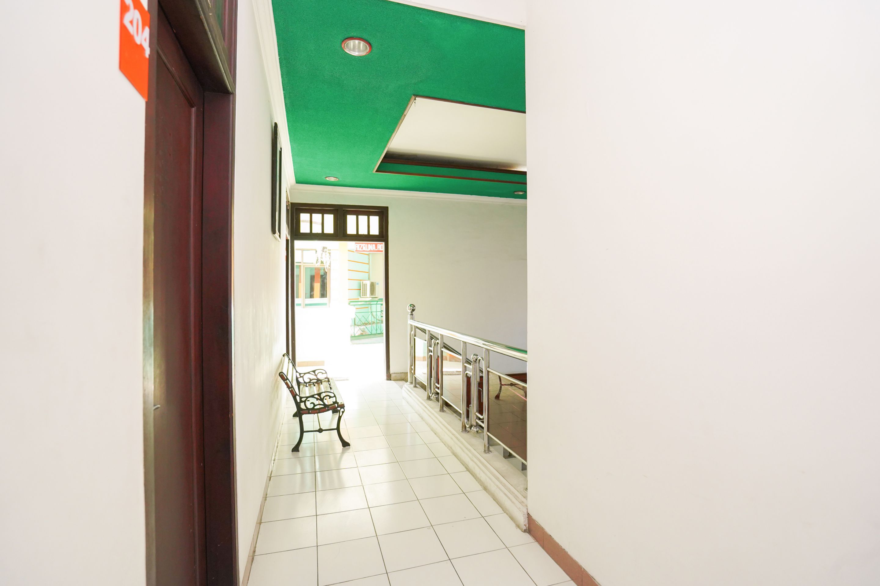 Um corredor com um banco, teto verde e porta que dá para um quarto.
