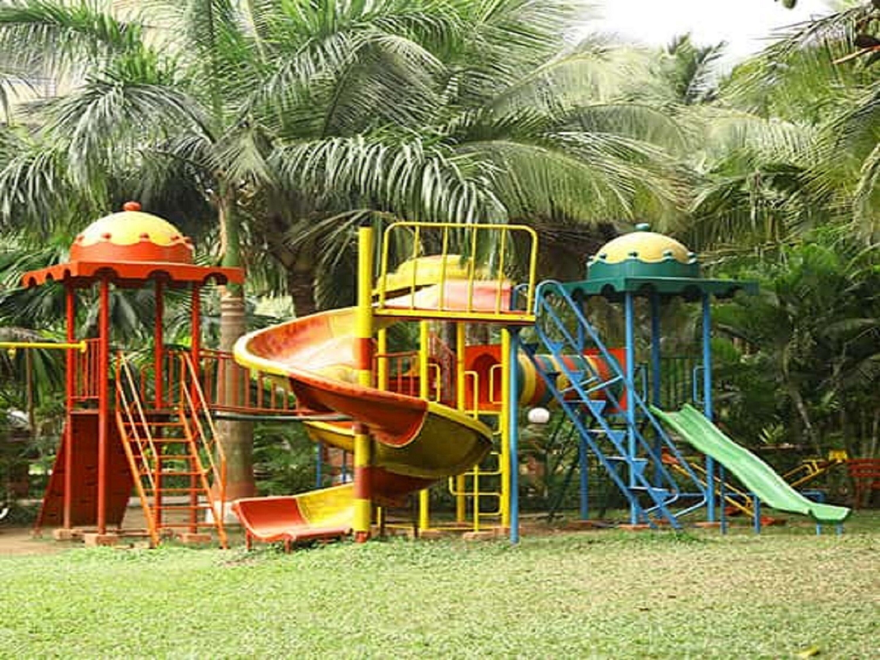Um parquinho com escorrega, estruturas de escalada e uma casinha em forma de cúpula.