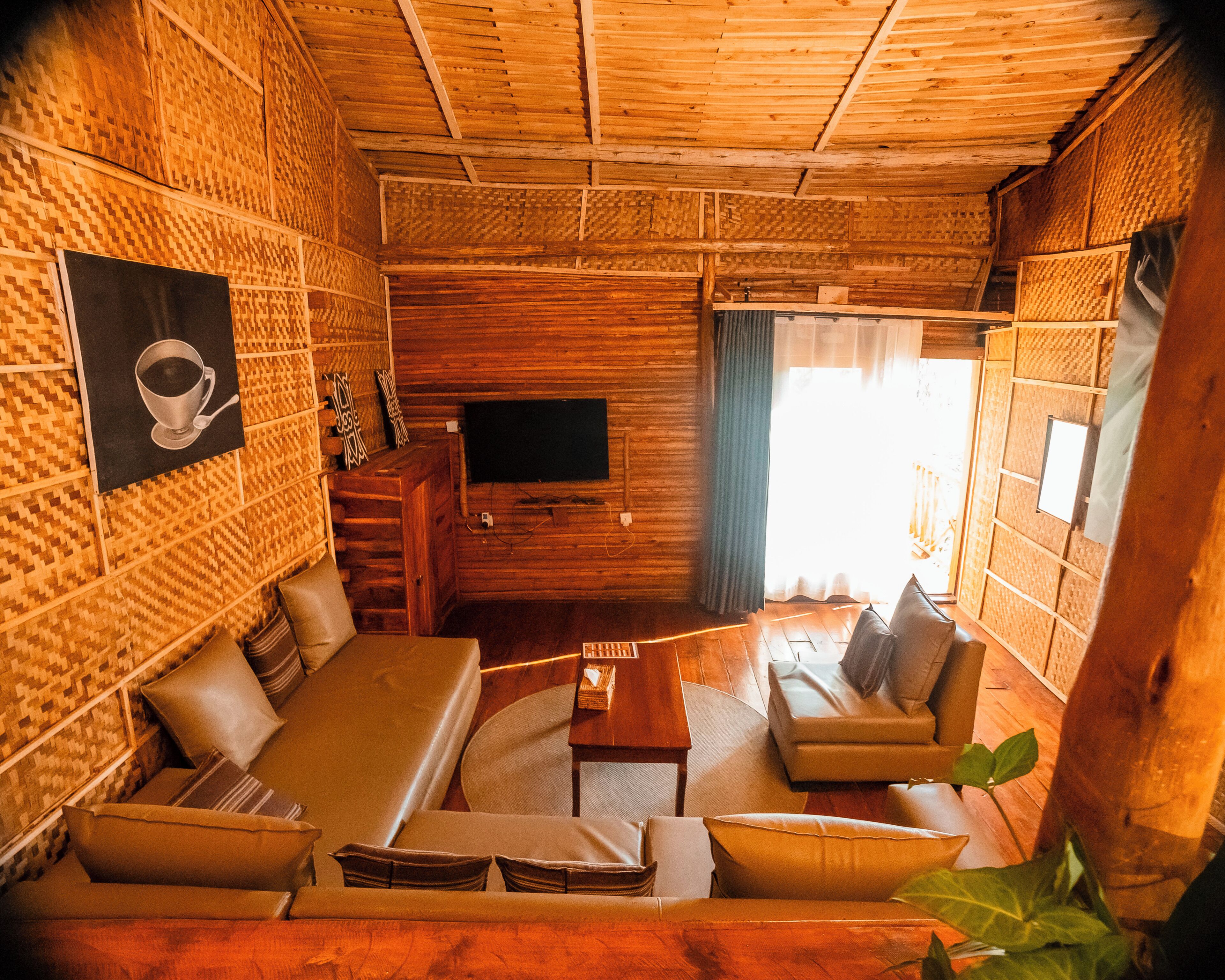 Um quarto com sofá, poltronas, uma mesa pequena e televisão.