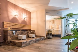 Uma casa de banho moderna com bancada de pedra, duas pias e um banco de madeira.