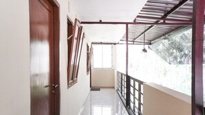 Um corredor com porta de madeira, janela e guarda-corrimão de metal.