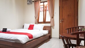 Quarto com cama de madeira, travesseiro vermelho e cadeira de madeira.