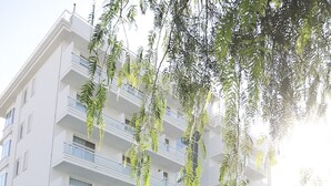 Um hotel moderno com piscina, rodeado por plantas em vasos e um deque de madeira.