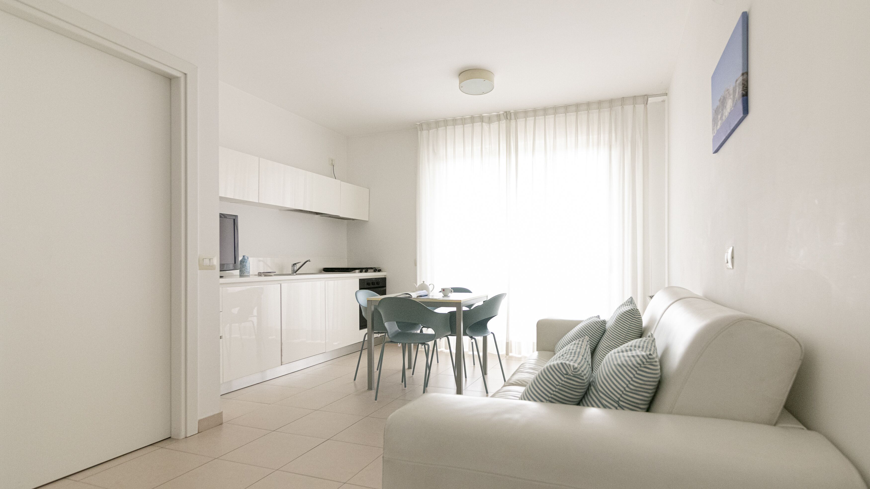 Uma sala de estar moderna e bem iluminada, com sofá e mesa de jantar.