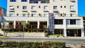 Um hotel moderno com fachada plana, várias varandas e uma entrada imponente.