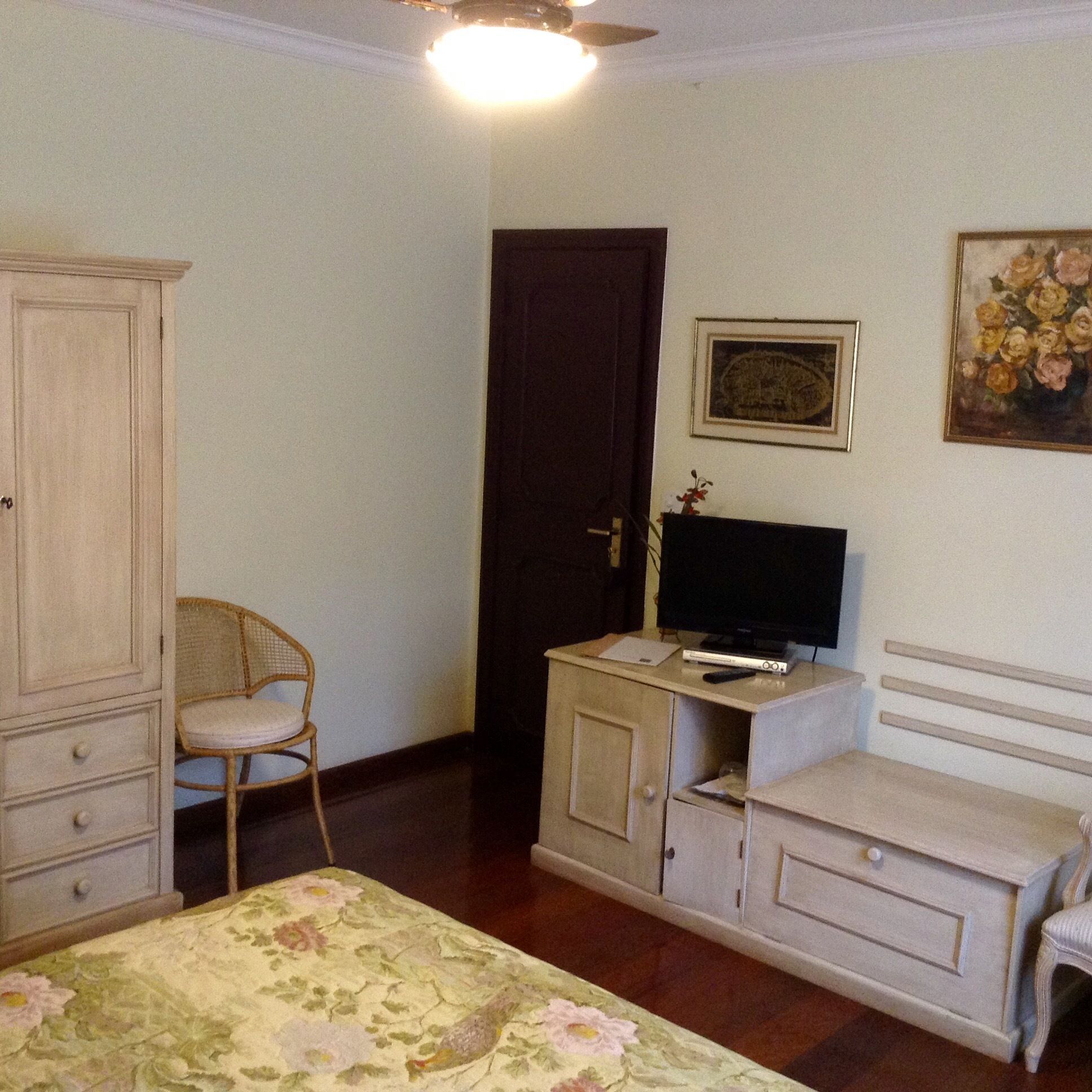 Quarto com cama, guarda-roupa, televisão e uma cadeira.