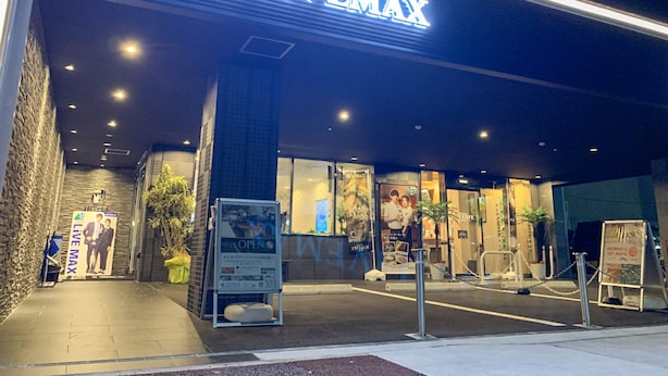Exterior do Hotel Livemax, com um letreiro iluminado em destaque, fachada moderna e entrada visível.