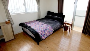 Quarto com cama, escrivaninha, cadeira, janela e ar condicionado.