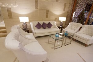 Uma sala de estar moderna com um sofá branco, duas poltronas e uma mesa de centro de vidro.