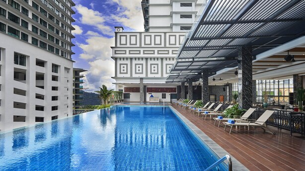 Piscina com espreguiçadeiras e vista para um edifício moderno.
