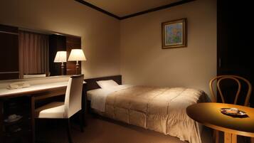 Quarto de hotel com cama, escrivaninha, cadeira e uma pequena mesa com prato e copo.