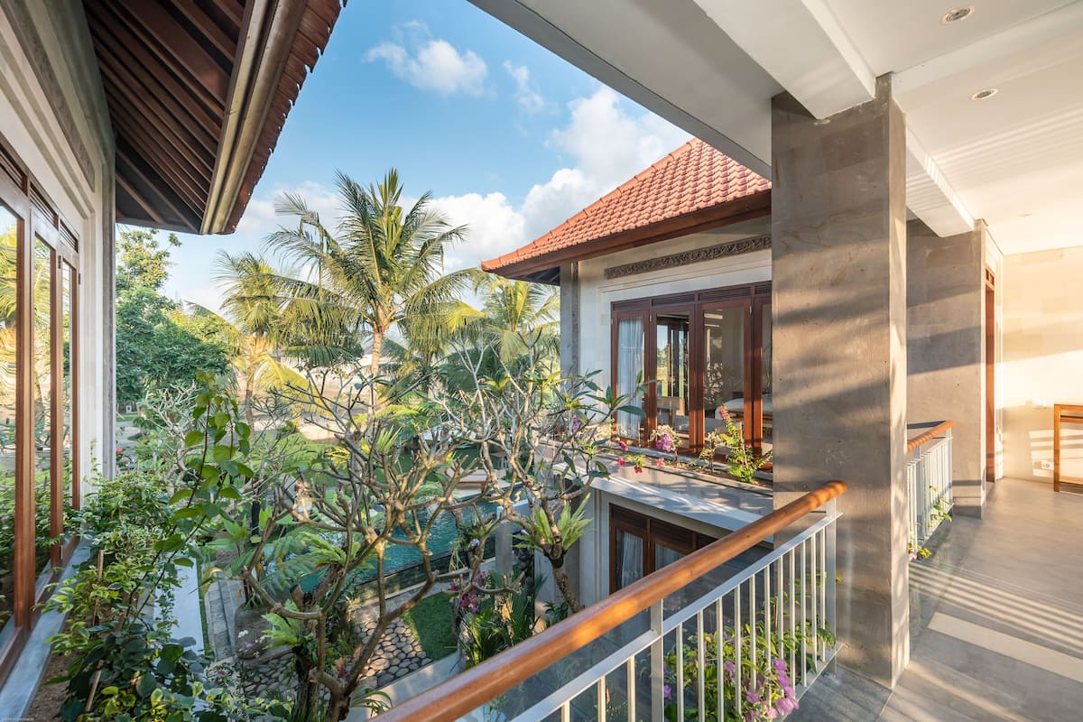 Varanda com vista para uma piscina e plantas tropicais.