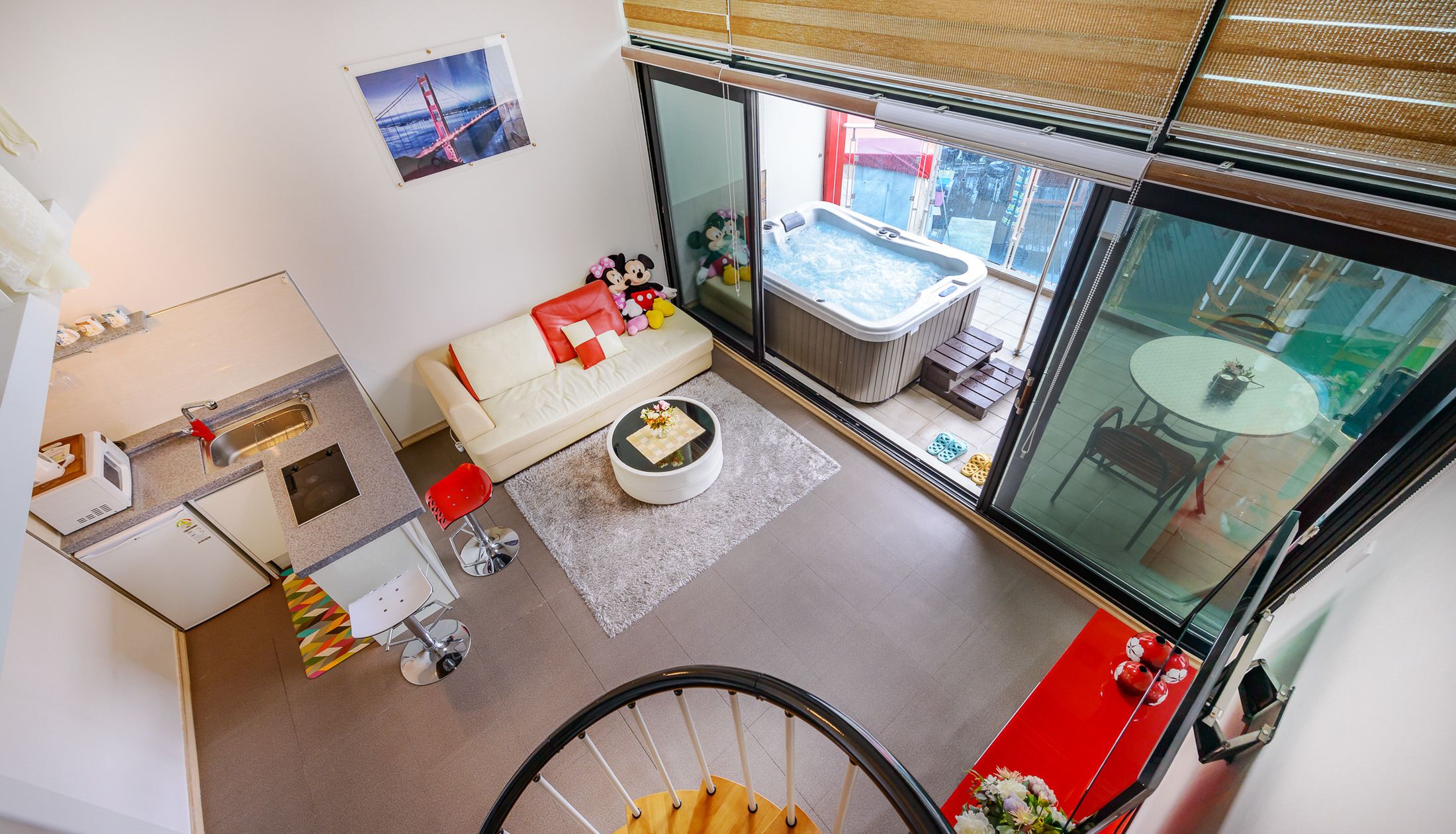 Um espaço de estar moderno com cozinha, sofá, banheira de hidromassagem e vista para o exterior.