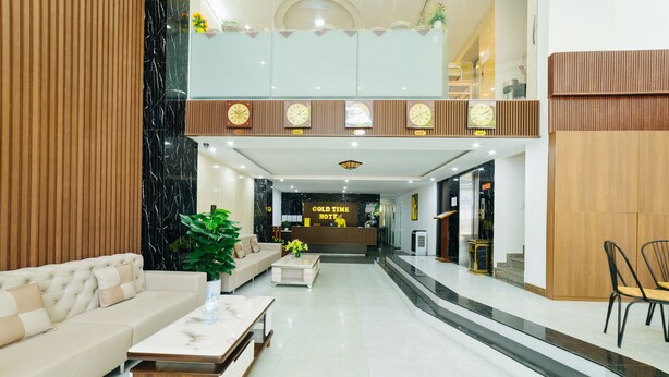 Um lobby de hotel moderno com uma mesa de recepção, área de estar e uma escadaria.