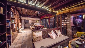 Um interior acolhedor e rústico, com um banco de madeira, estantes com livros e uma área de cozinha.