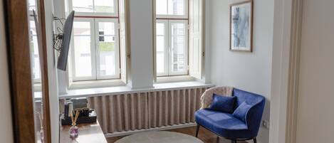 Um quarto com um sofá azul, um tapete redondo e um radiador.