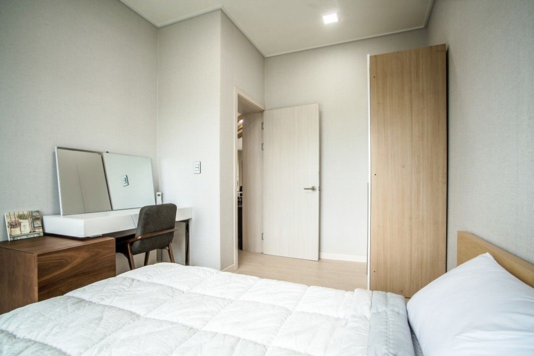 Um quarto com cama, escrivaninha, cadeira, guarda-roupa e espelho.