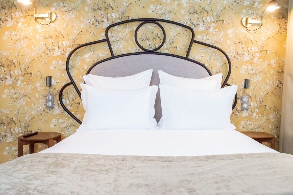 Cama bem arrumada com lençóis brancos e cabeceira com design circular.