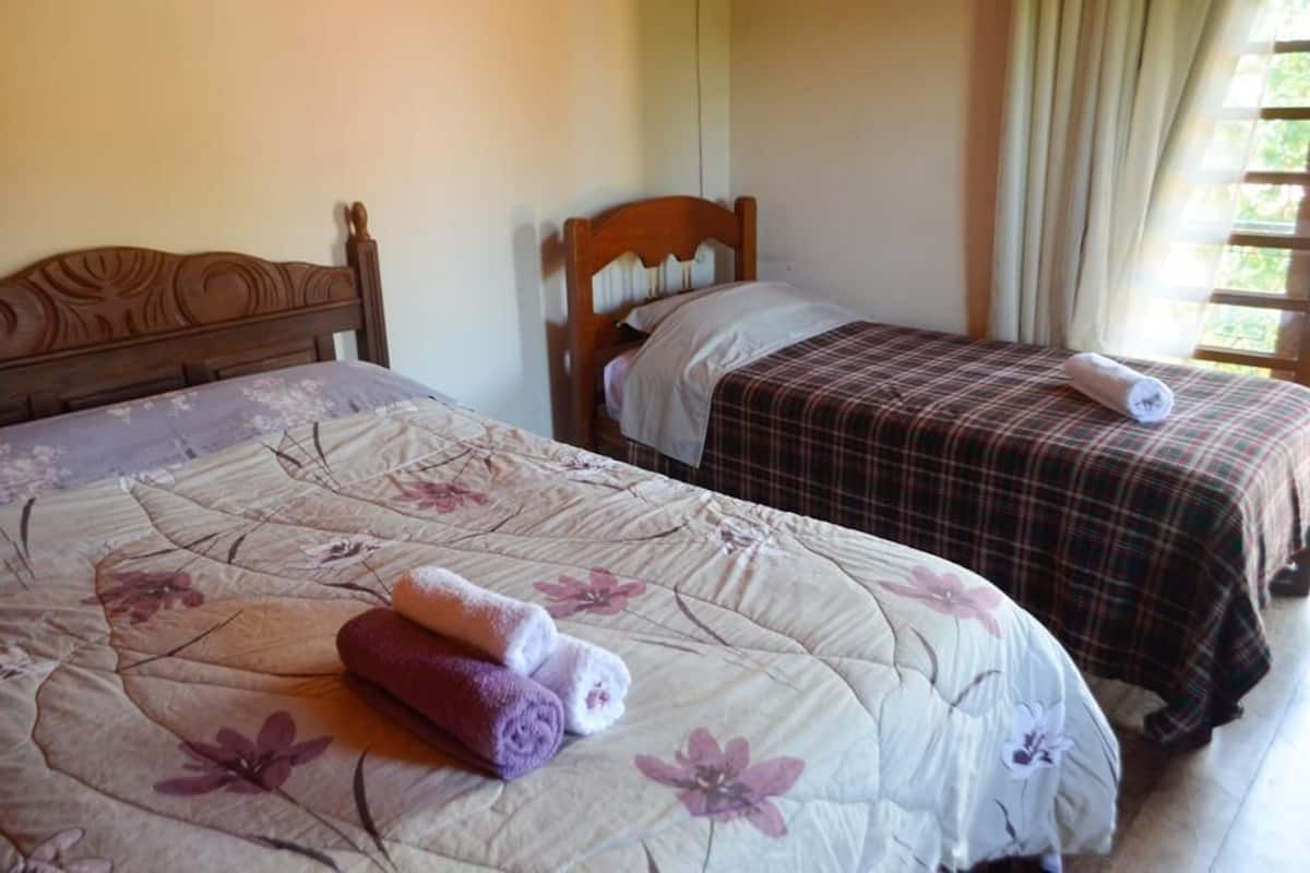 Duas camas de solteiro com cabeceiras de madeira, roupa de cama florida e toalhas enroladas.