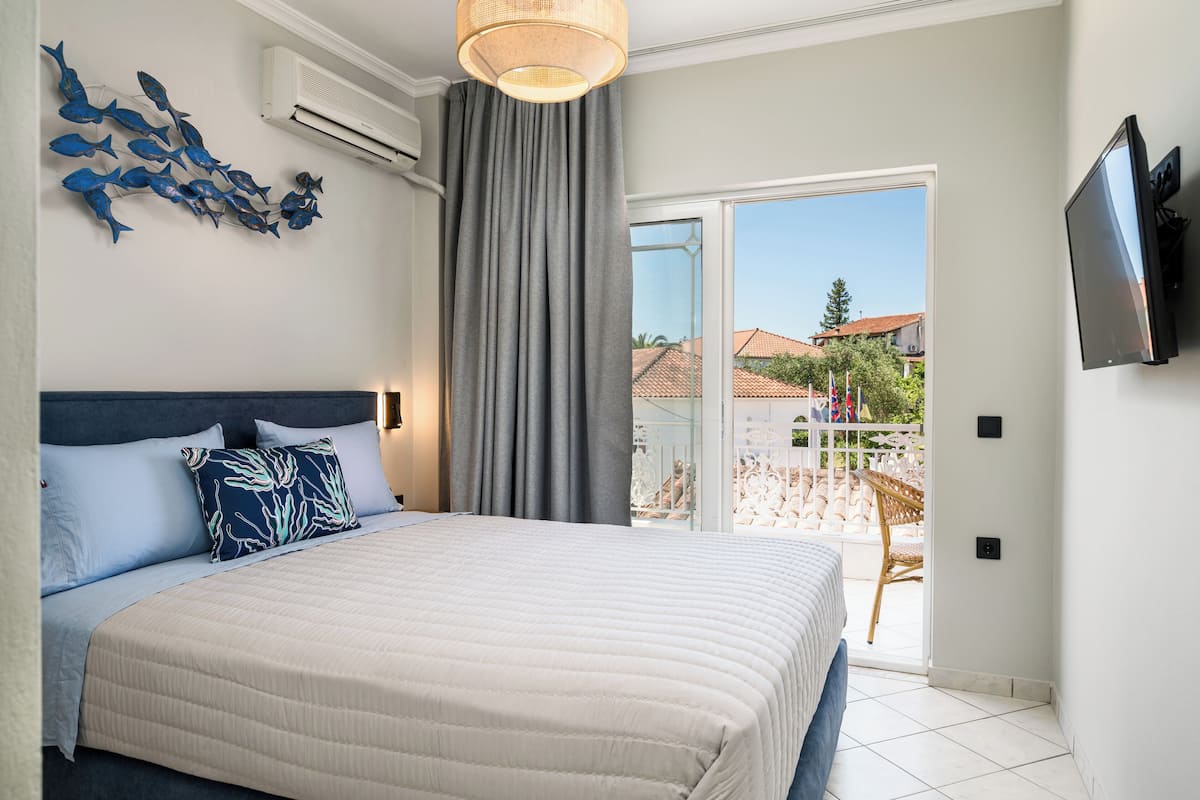Quarto com uma cama grande, vista para o exterior, televisão e ar condicionado fixado na parede.