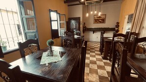 Uma sala de jantar com mobiliário de madeira, piso xadrez e vista para o exterior através de uma janela.