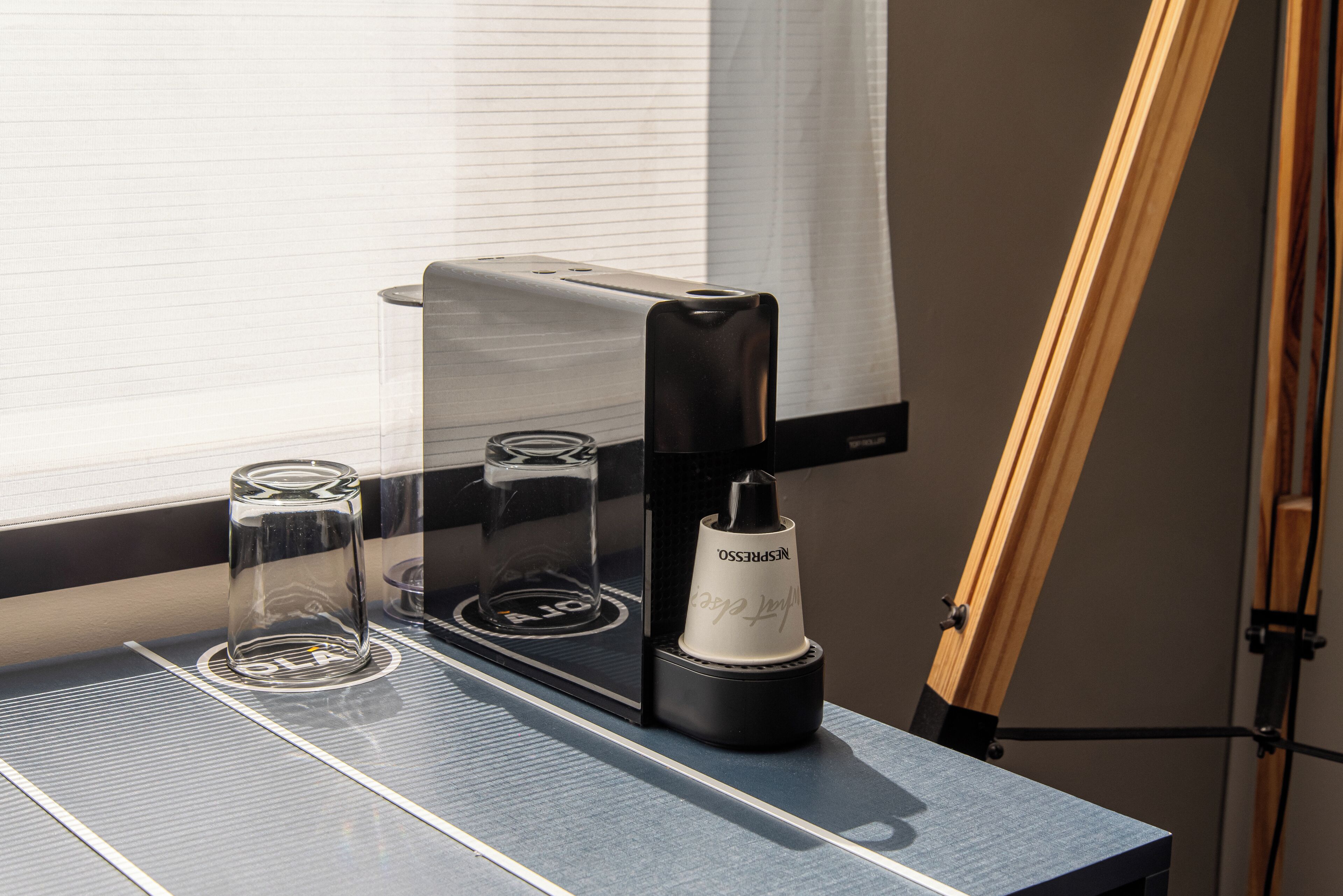 Uma máquina de café sobre uma mesa, com duas taças e uma chávena.
