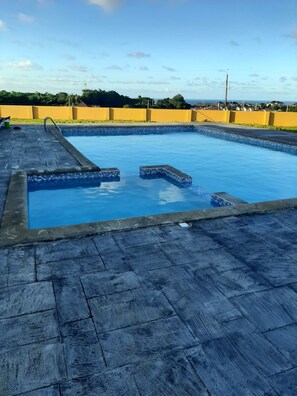 Uma piscina com borda azulejada e área pavimentada ao redor.