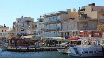 Orla marítima com barcos atracados, um restaurante flutuante e edifícios altos.