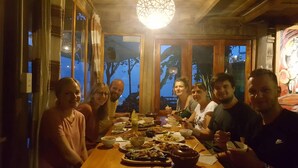 Um grupo de pessoas jantando em uma mesa de madeira, com diversos pratos e tigelas.
