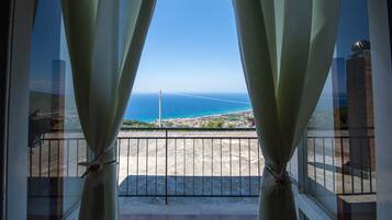 Uma varanda com vista para o mar e uma linha de eletricidade ao longe.