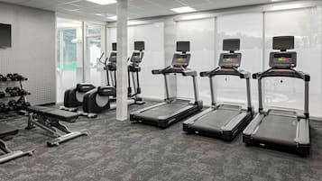 Uma academia equipada com esteiras, halteres e bancos de musculação.