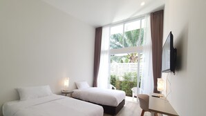 Quarto de hotel com duas camas, uma escrivaninha, uma cadeira, televisão e janela com cortinas.