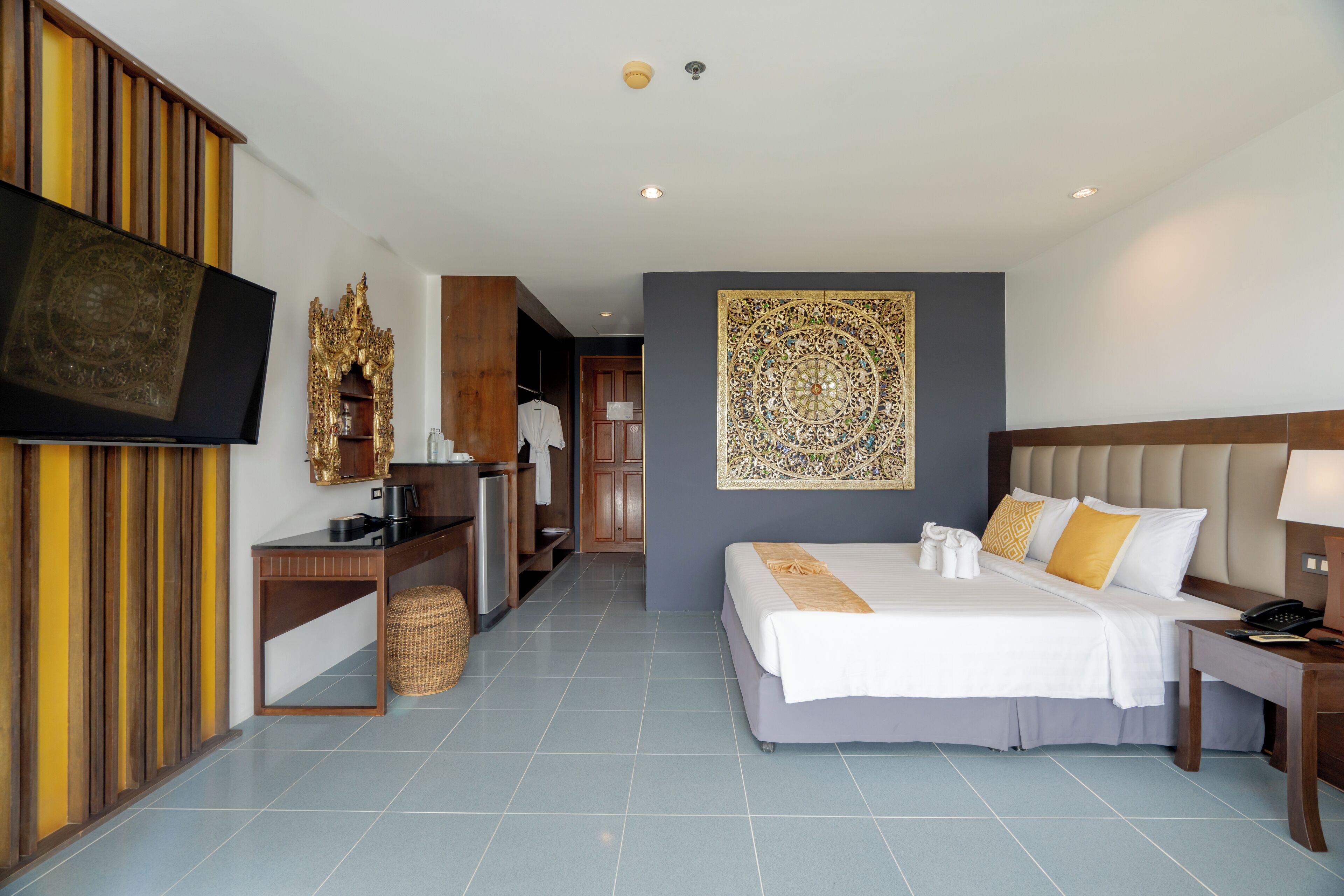Quarto de hotel com cama, mesa de cabeceira, televisão e um objeto decorativo na parede.