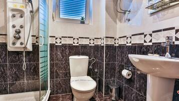 Uma casa de banho moderna com chuveiro, sanita e lavatório.