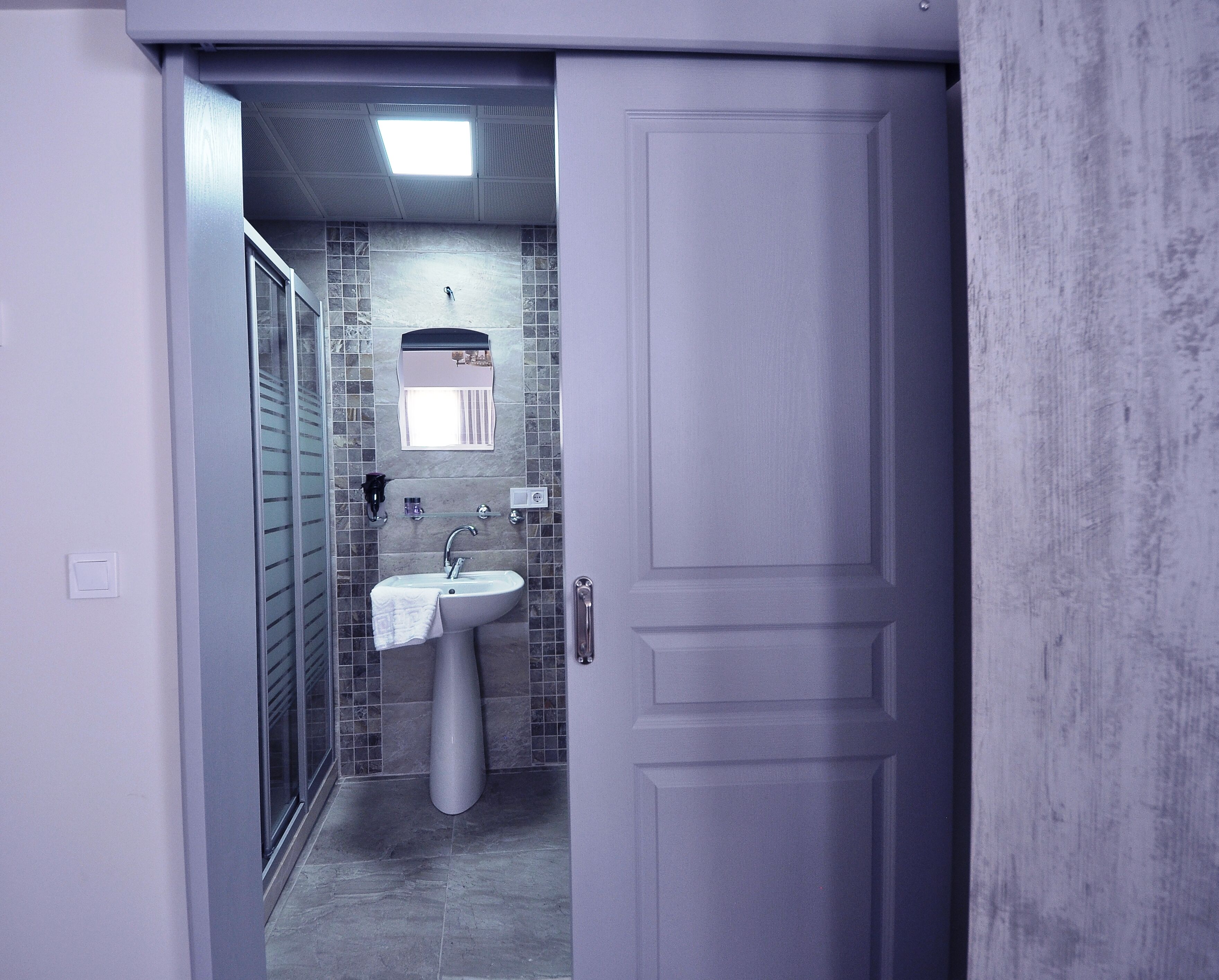 Casa de banho com lavatório branco, espelho e zona de duche.