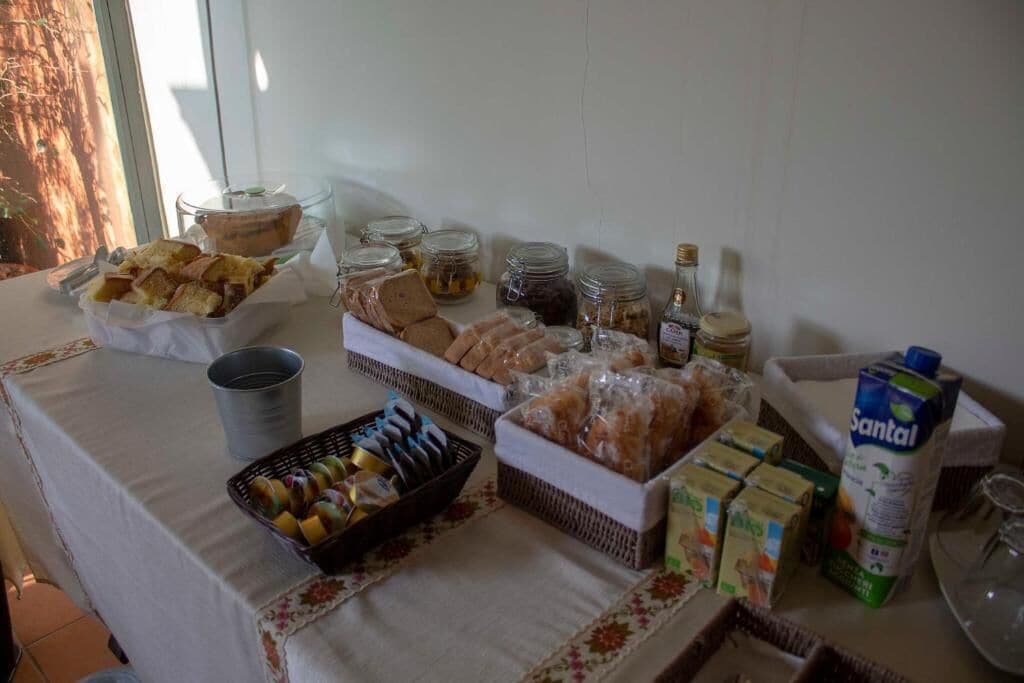 Mesa de buffet com diversos alimentos, incluindo pães, doces e acompanhamentos.
