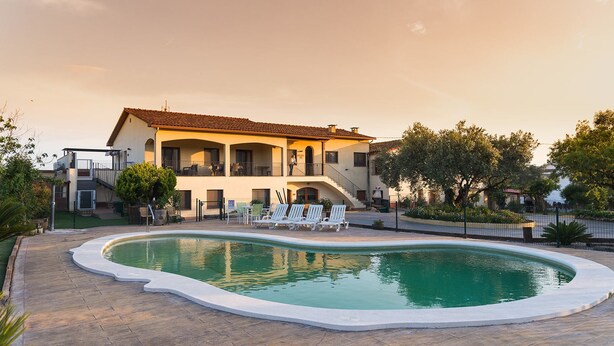 Uma casa grande com piscina, área de estar ao ar livre e um terraço coberto.