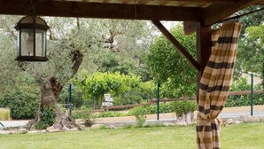 Uma área externa coberta com estrutura de madeira, um candeeiro pendurado e um tecido xadrez.