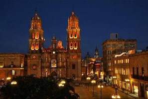 Um edifício histórico com duas torres imponentes, rodeado por ruas e edifícios urbanos.