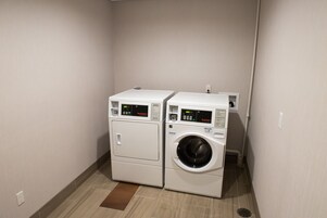 Uma lavanderia com dois eletrodomésticos empilhados, um secador e uma máquina de lavar, ambos com mostradores digitais.
