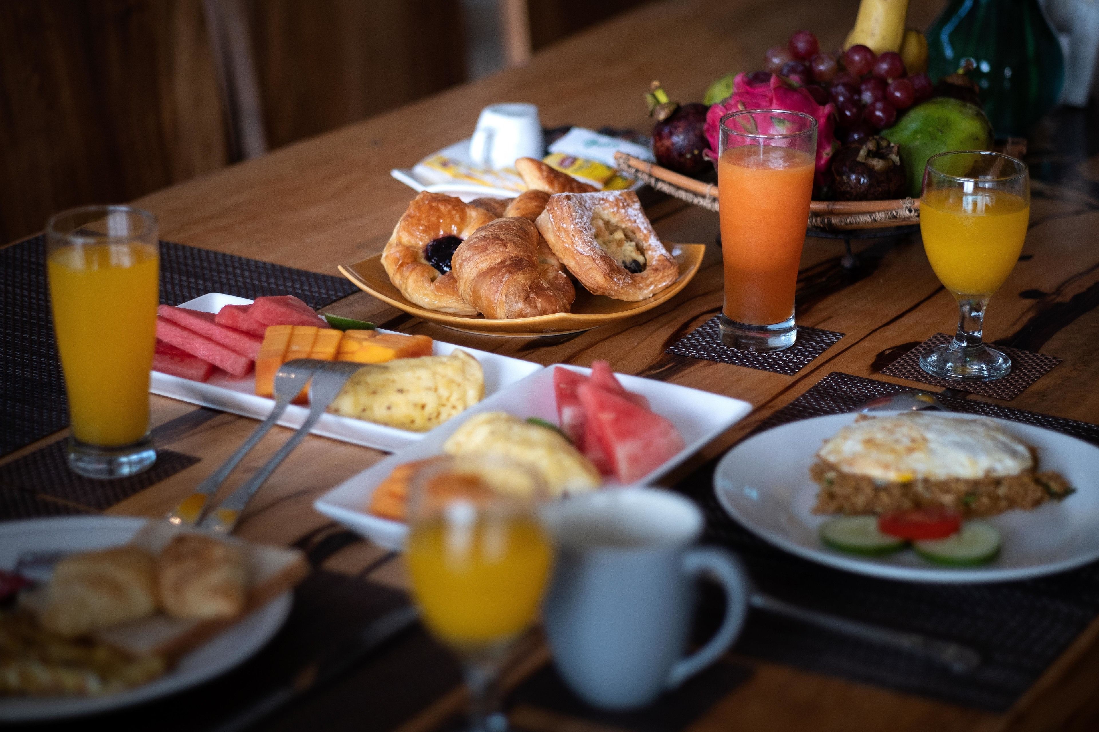 Uma mesa de café da manhã com croissants, frutas e bebidas.
