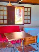 Quarto com mesa de madeira, sofá vermelho e uma cama.